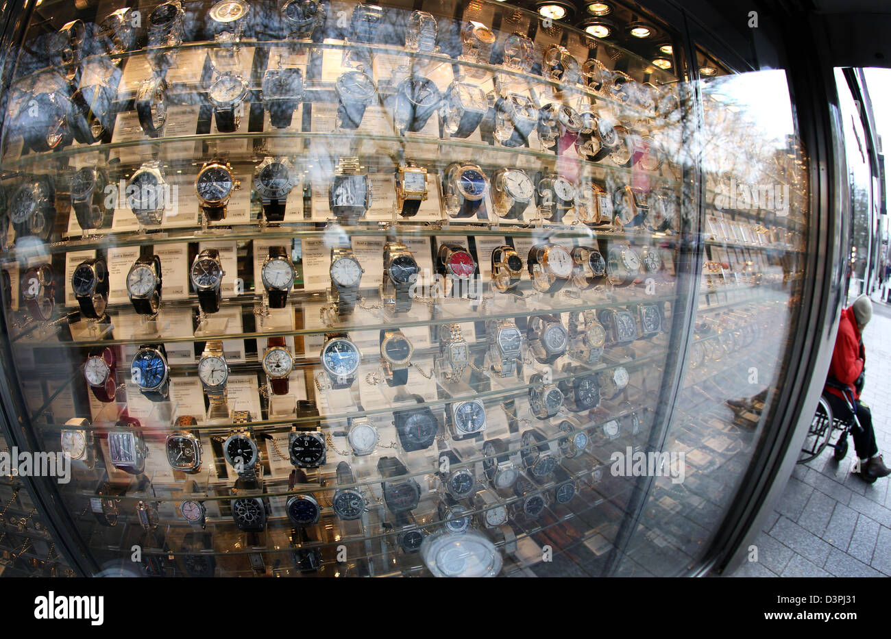 A beggar sits next to a shop window displaying luxury watches at ...
