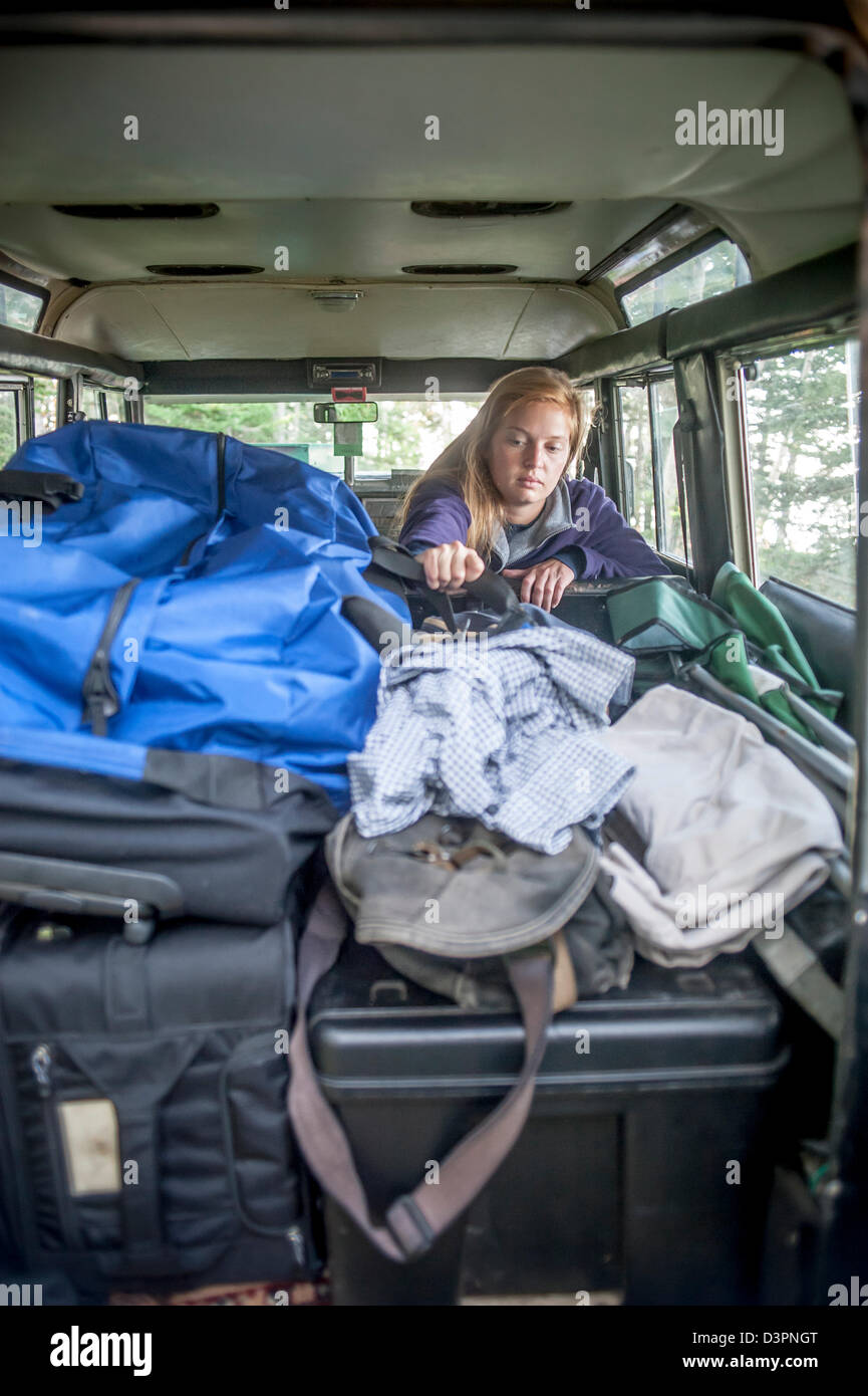 Young woman packing camping gear in classic SUV Acadia National Park ...