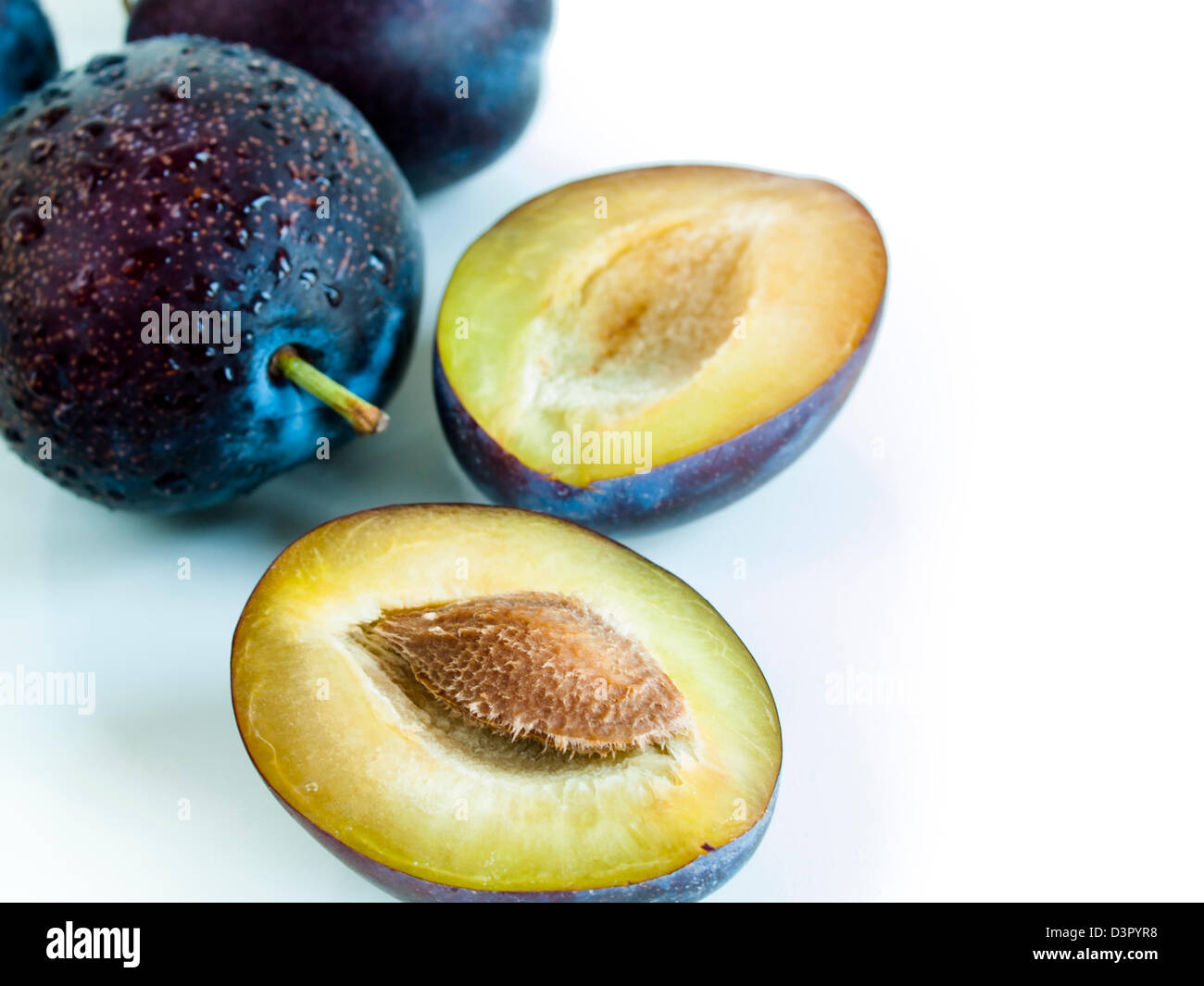 Fresh plums with one cut plum on white background Stock Photo - Alamy