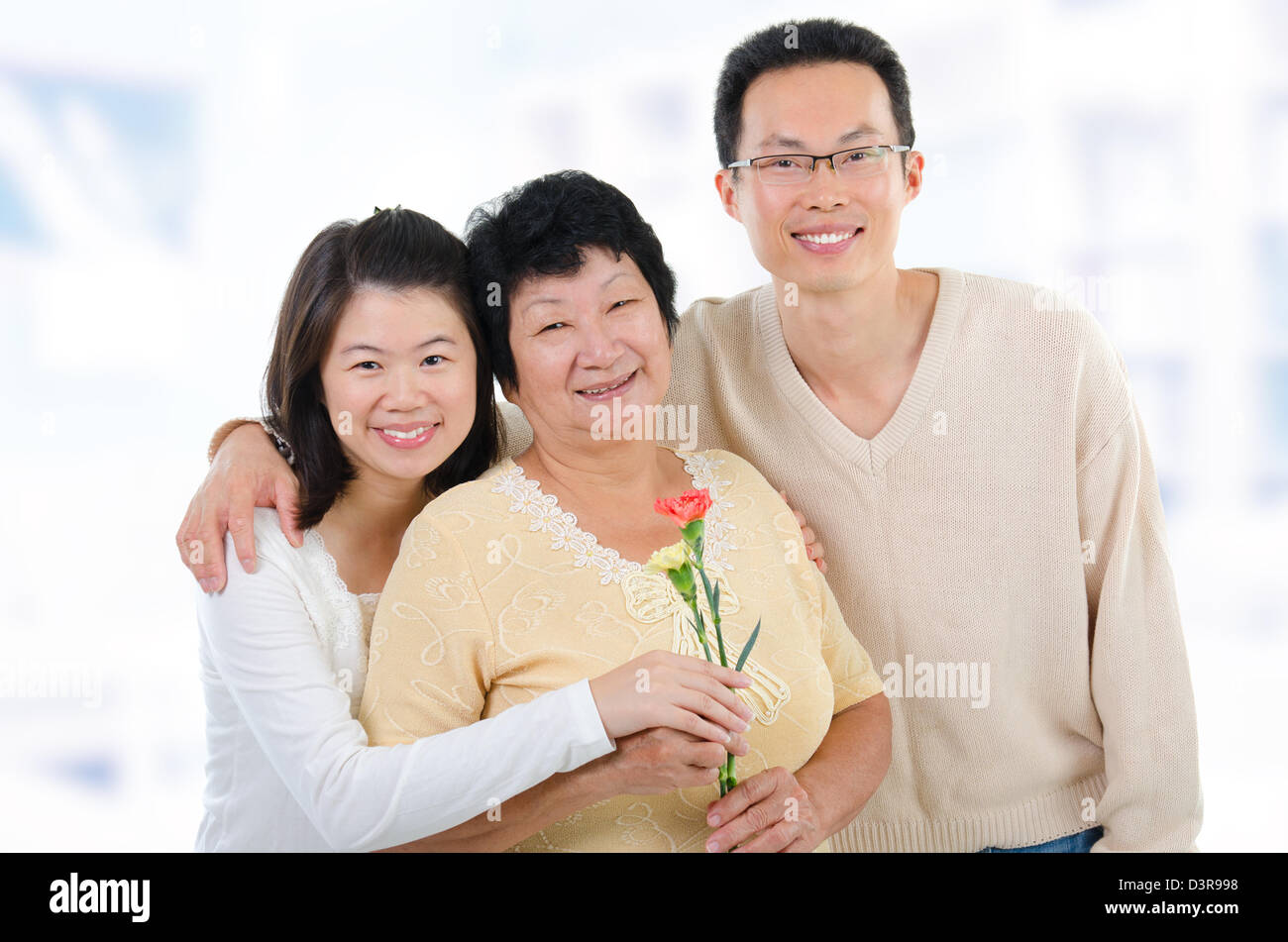 Asian family at home. Adult offsprings giving carnation flowers to ...