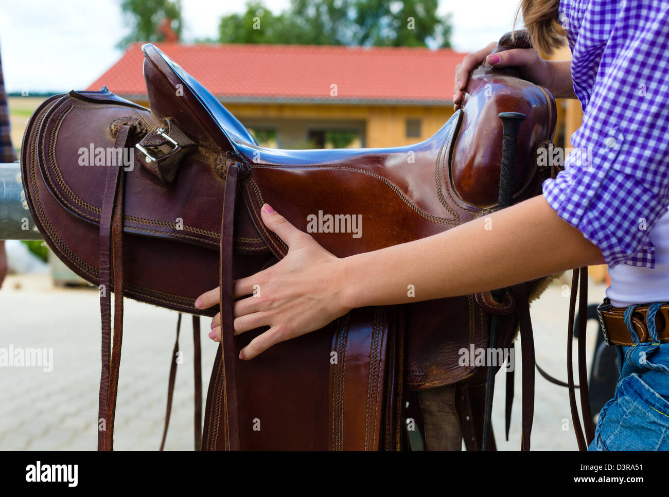 Young woman keeping a saddle in the hand showing it Stock Photo - Alamy
