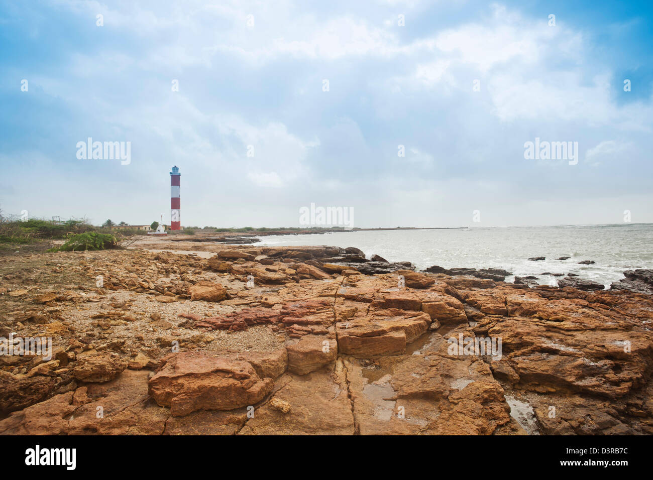 Rock formations at the coast with lighthouse in the background, Dwarka ...