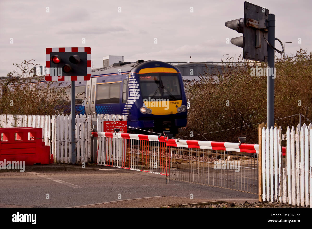 Scotrail commuter train approaching a level crossing travelling away ...