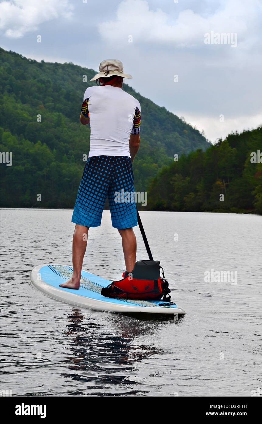 Man on a paddleboard with his gear on board enjoying the beautiful ...
