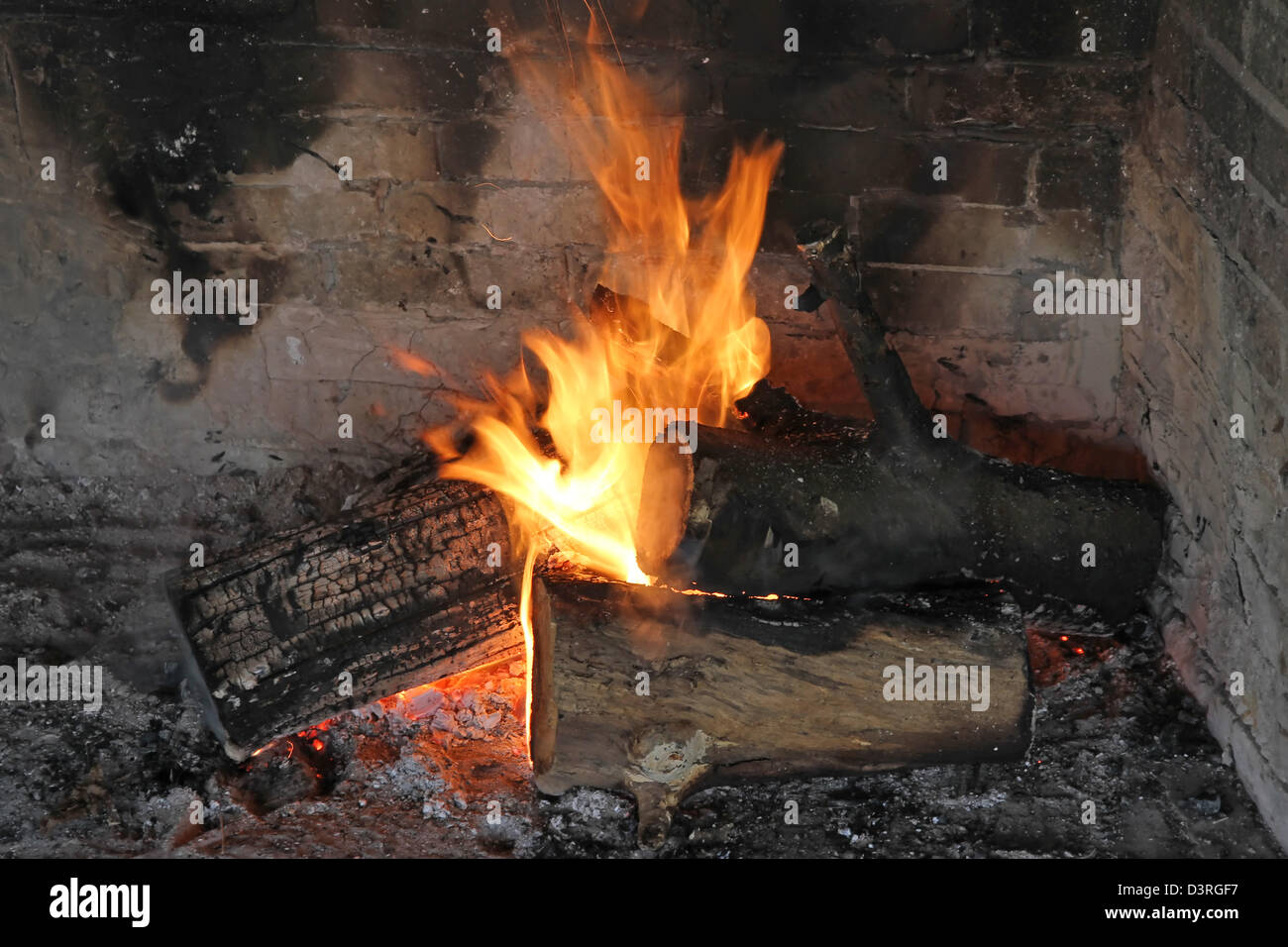 Three logs burning in an outdoor fire place Stock Photo - Alamy