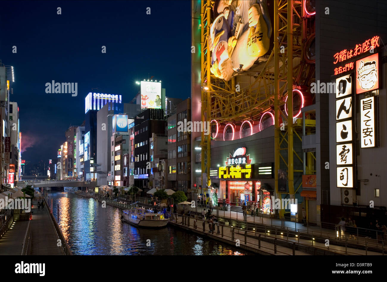 Sightseeing boat moves slowly past neon signs along Dotonbori-gawa ...