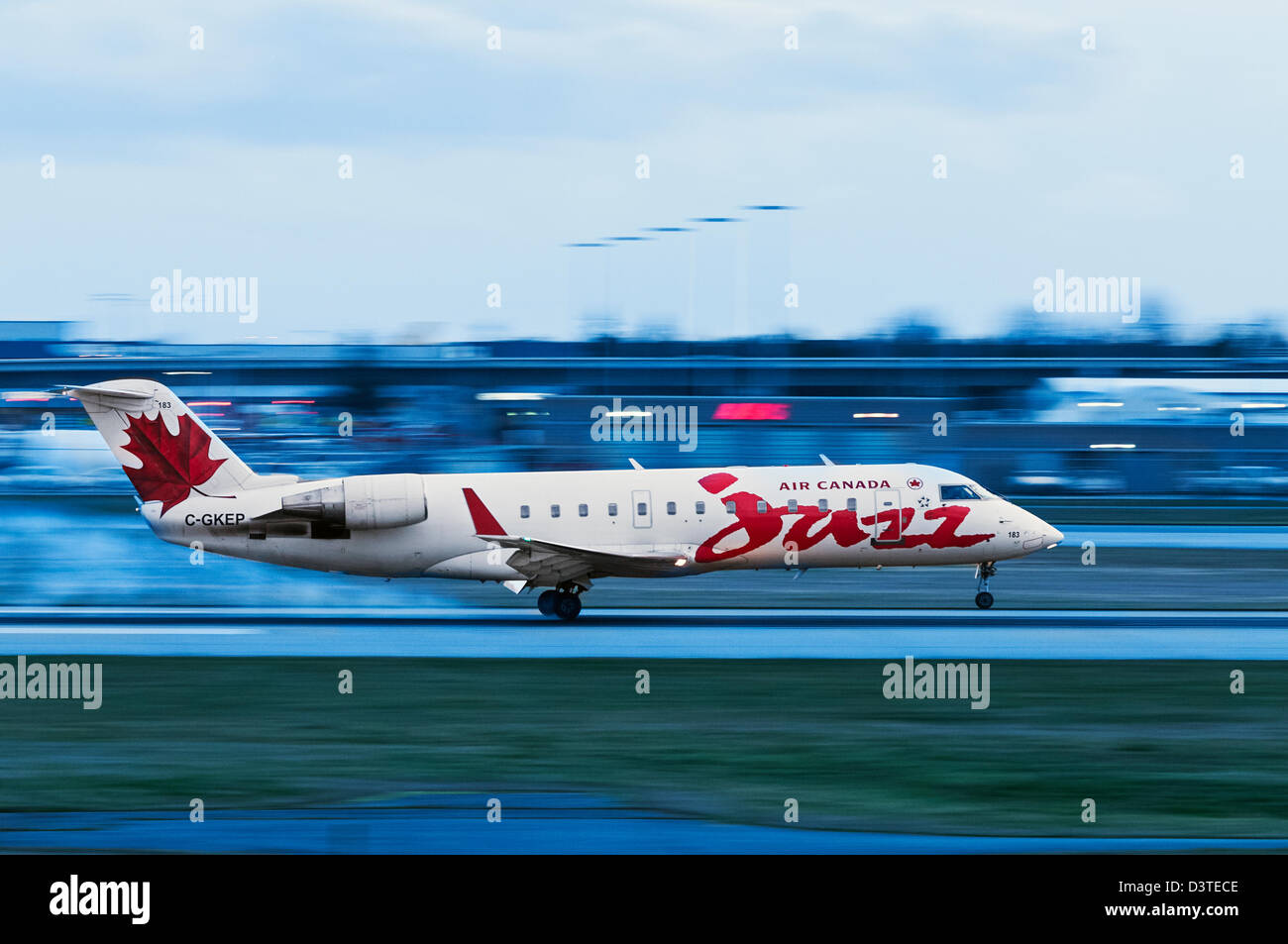 An Air Canada Jazz CRJ-200ER regional passenger jet lands at twilight ...