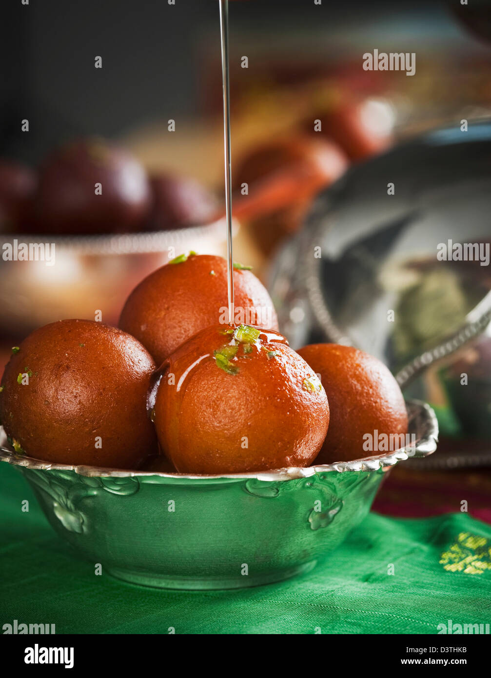 Sugar syrup being poured on gulab jamuns in a bowl Stock Photo - Alamy