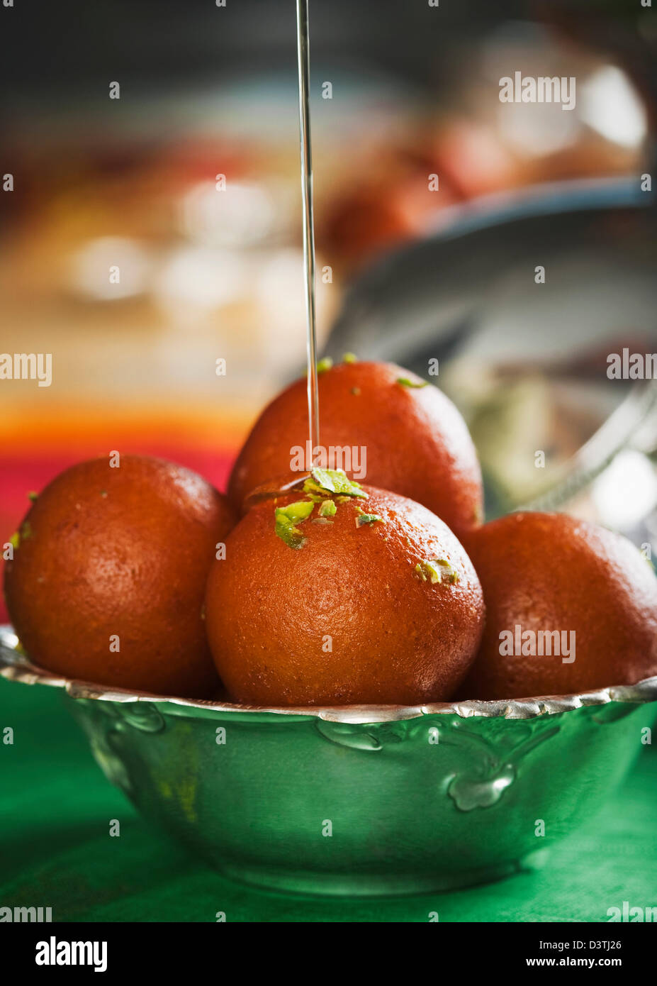 Sugar syrup being poured on gulab jamuns in a bowl Stock Photo - Alamy