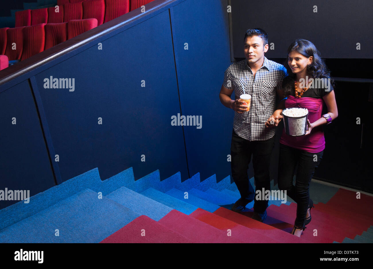 Couple moving up on steps in a cinema hall Stock Photo - Alamy