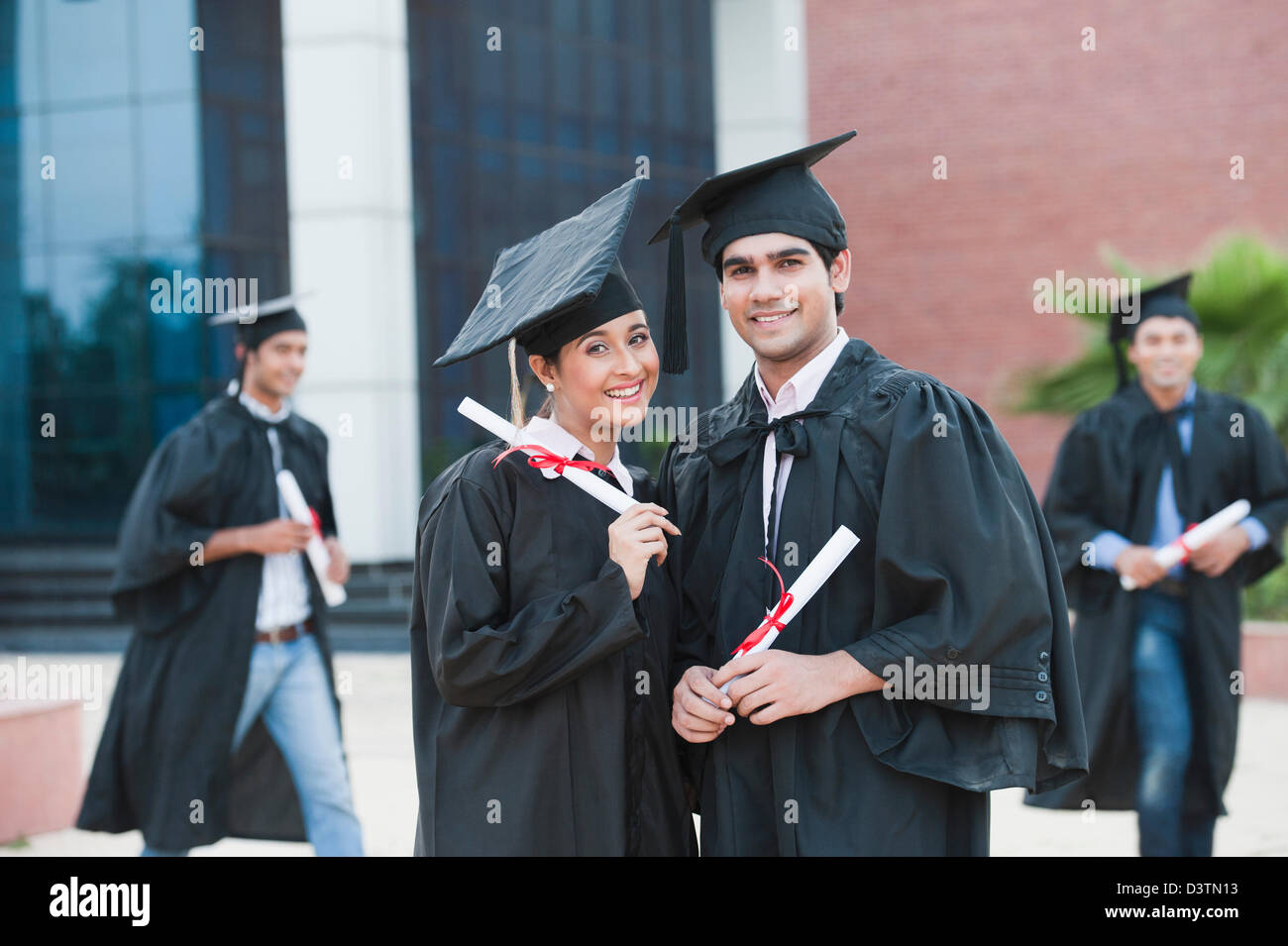Portrait of graduate students holding diplomas and smiling in ...
