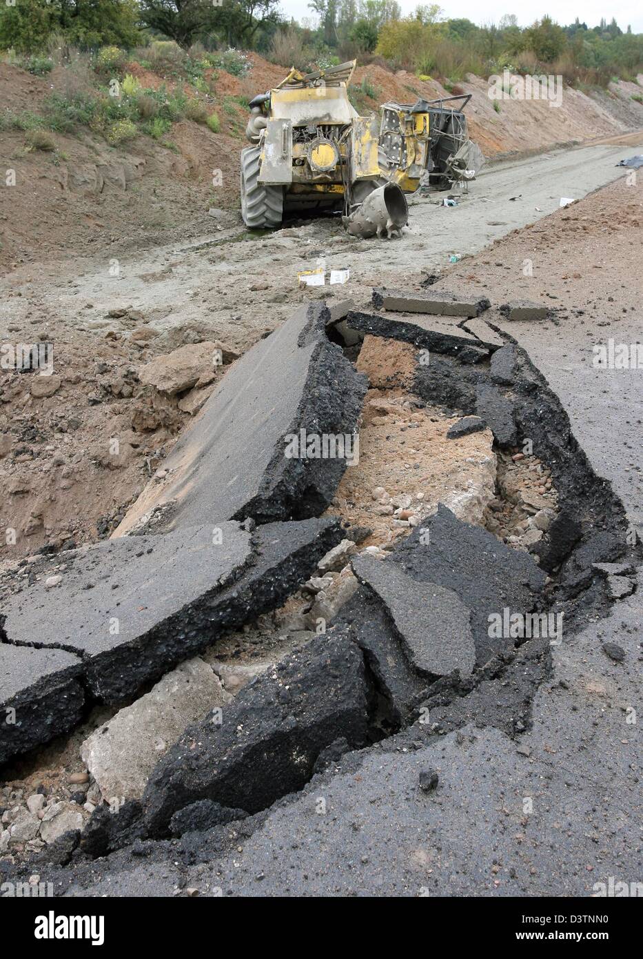 The photo shows a destroyed construction site vehicle (background) and ...