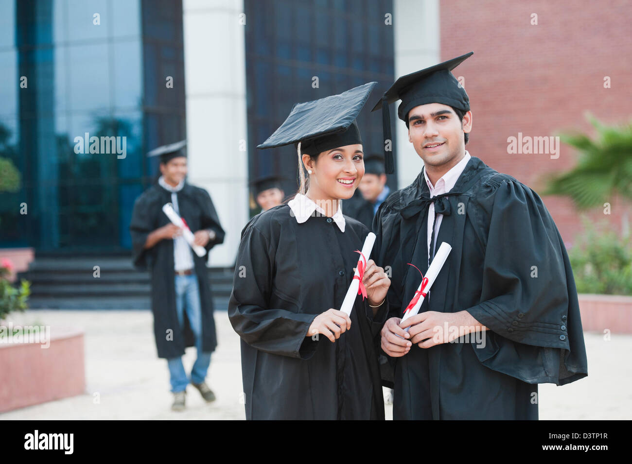 Portrait of graduate students holding diplomas and smiling in ...
