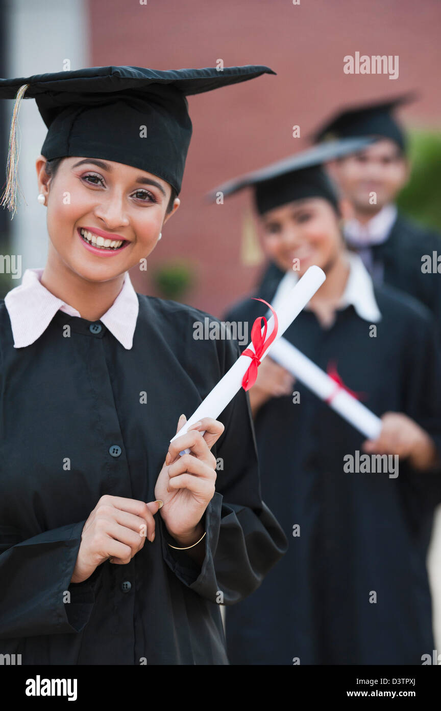 Portrait of graduate students holding diplomas and smiling in ...