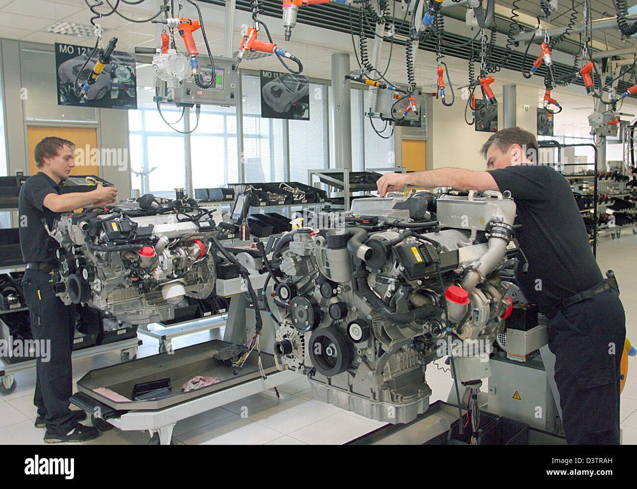 Two mechanics of AMG work on engines in the production site ...