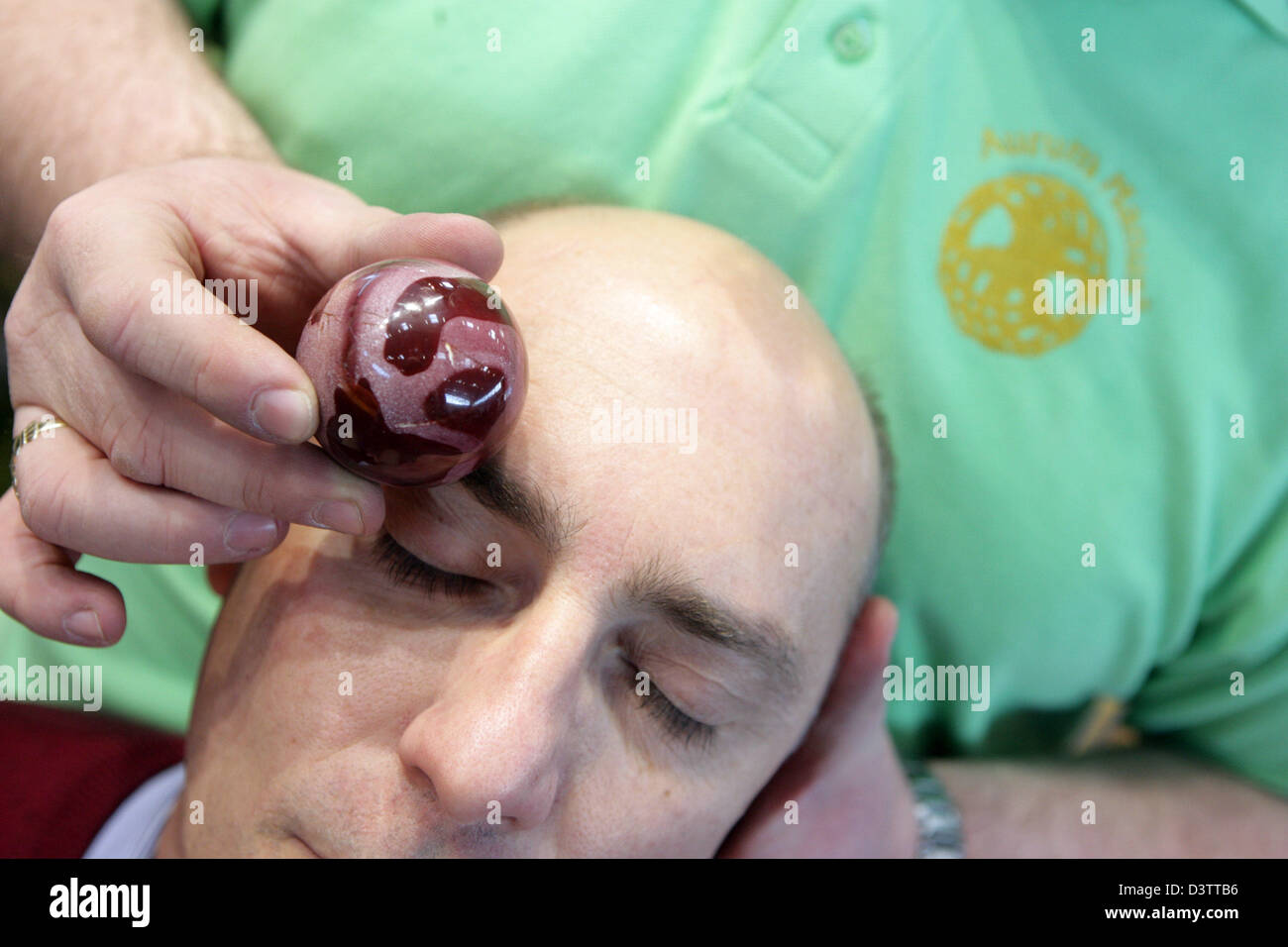 A masseuse treats a man's forehead with a rock crystal during the ...