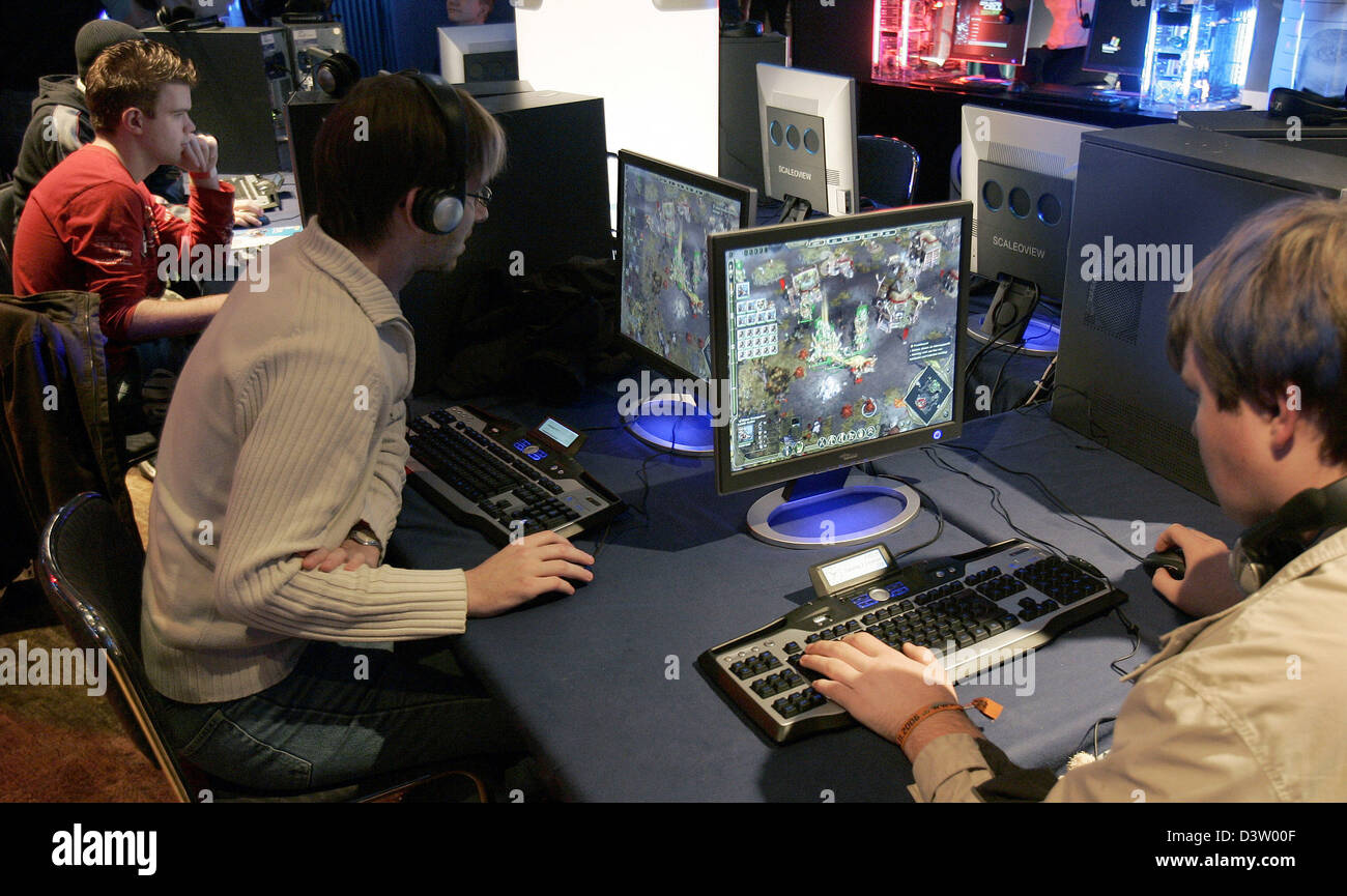 Young people sit in front of computer screens and play the game ...