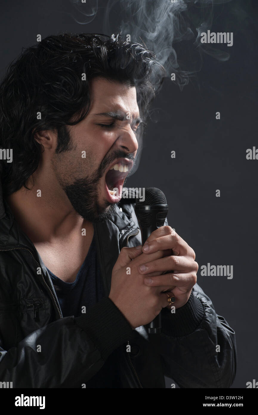 Singer holding a mike and singing Stock Photo - Alamy