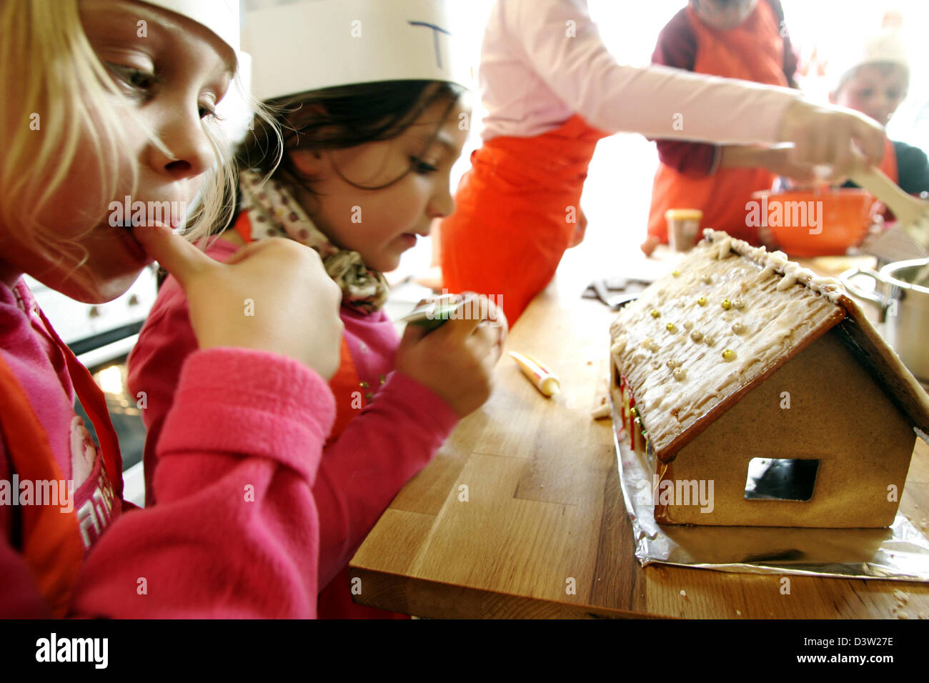 Nele and Tara (from L-R) decorate a gingerbread witches house during ...