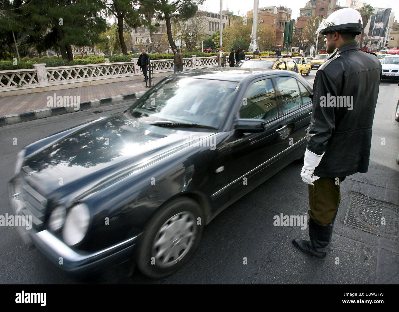 A black deluxe saloon car passes a police officer in Damascus, Syria, 4 ...