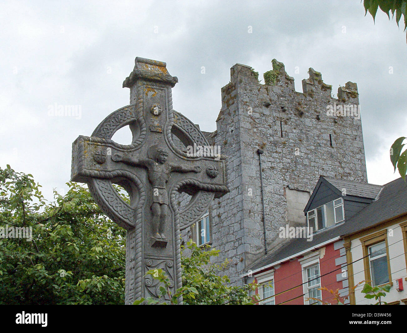 The pictures shows a stone cross in front of the Rock of Cashel in ...