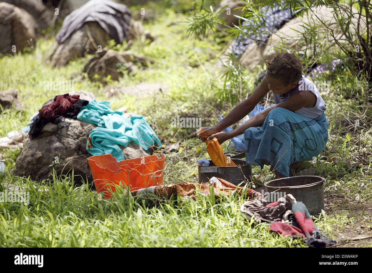 A young woman does the washing with two water-filled buckets, while the ...