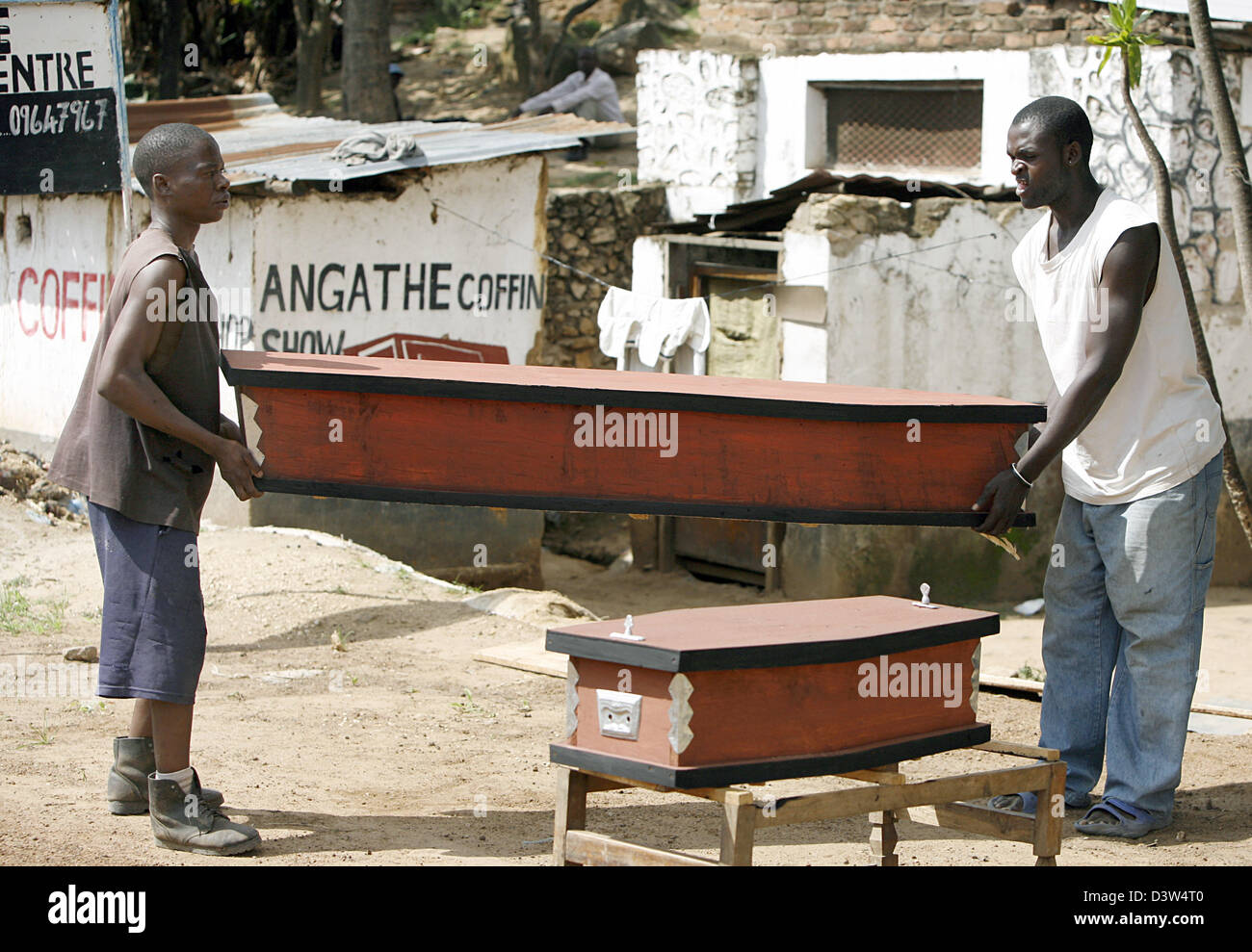 Two coffinmaker carry a finished coffin in front of their workshop in ...