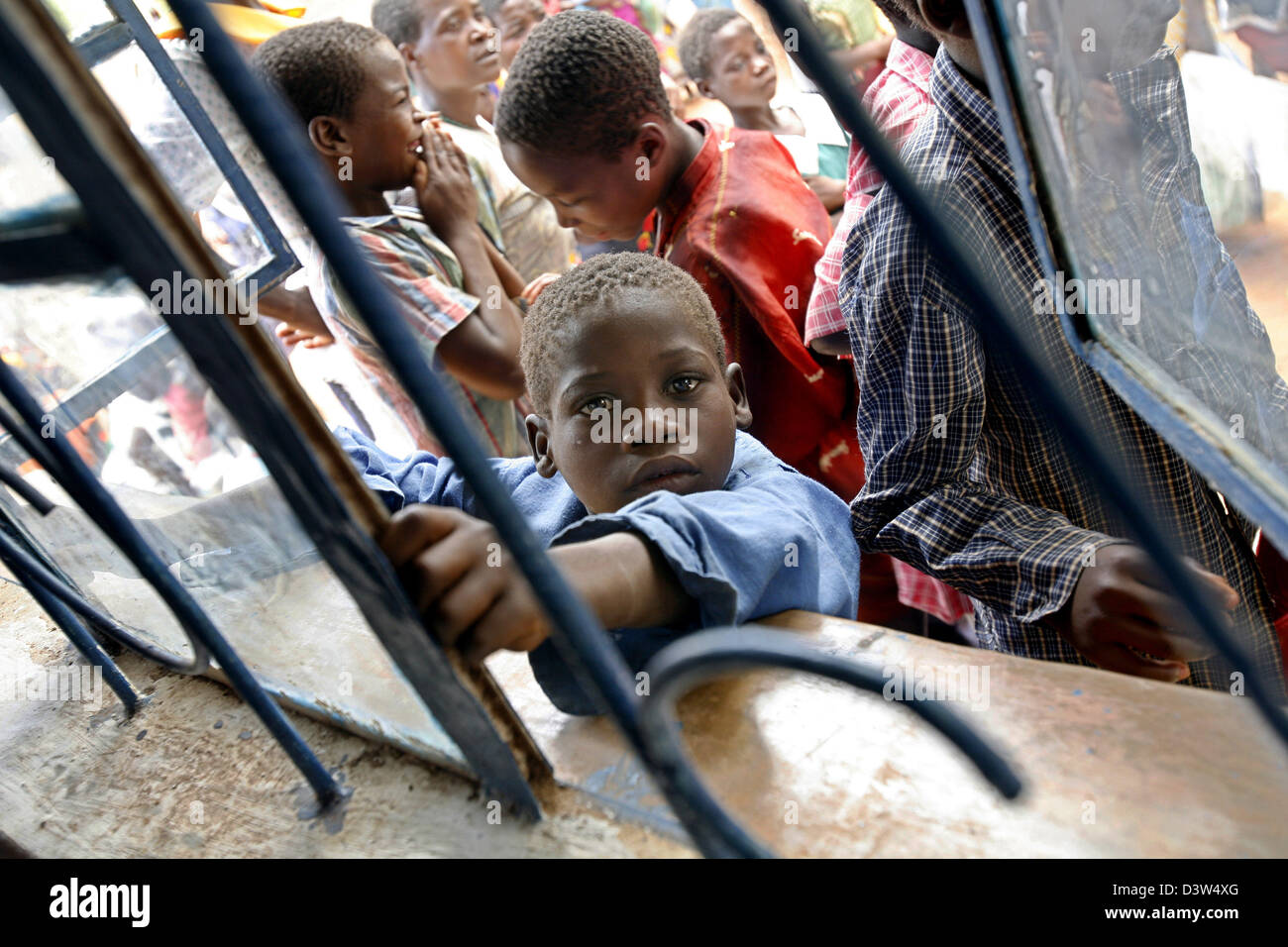 A boy peeks through a window into the community house in the village of ...