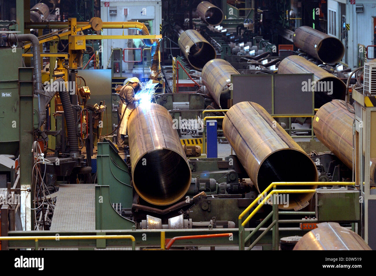 An employee with a protective mask works on pipes with a welding ...