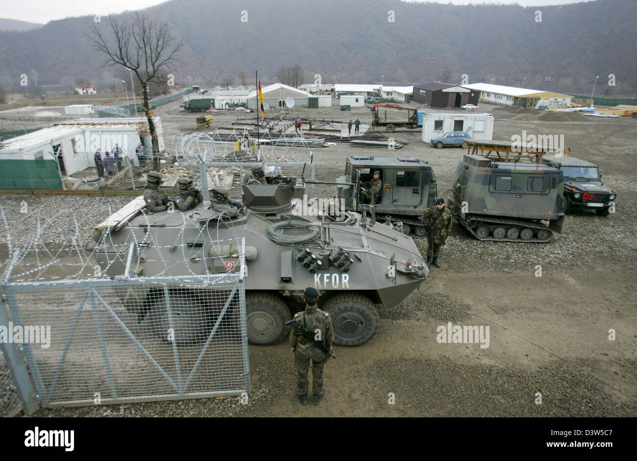 An armoured KFOR vehicle passes the gate of the fortified Bundeswehr ...