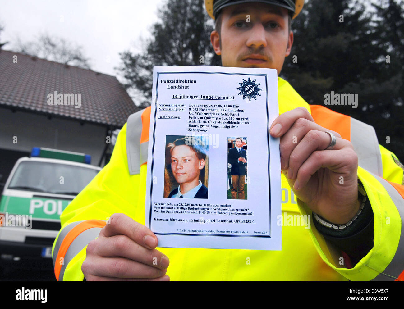 A policeman shows a paper with photos and a description of the missing ...