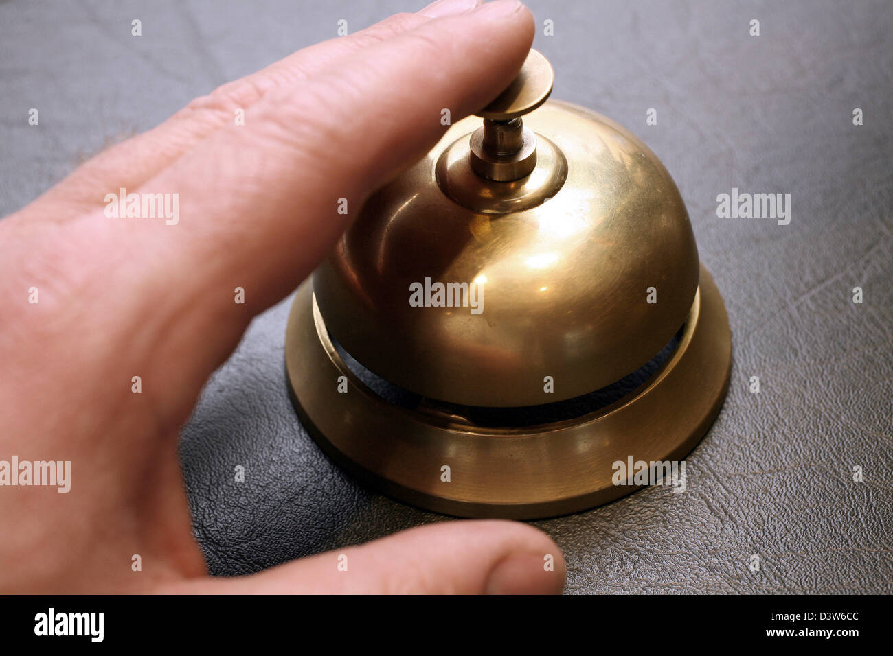 A hand presses the brass bell at a hotel reception in Frankfurt Main ...