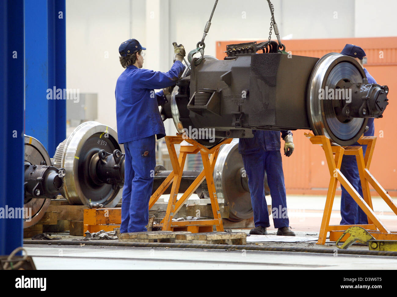 Mechanics change an axle of a S-Bahn regional train at a railway repair ...