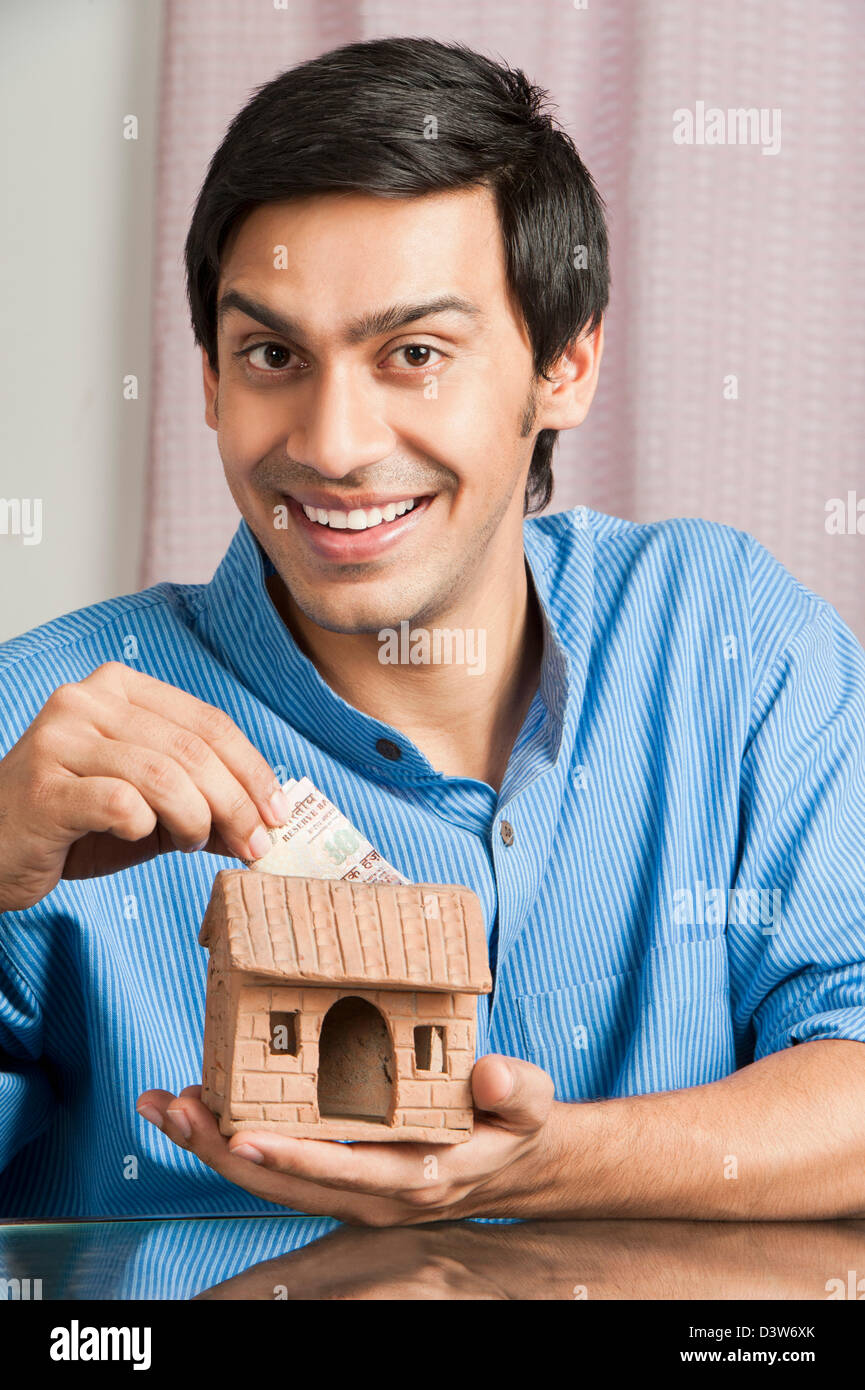 Bengali man putting money in a model home Stock Photo - Alamy