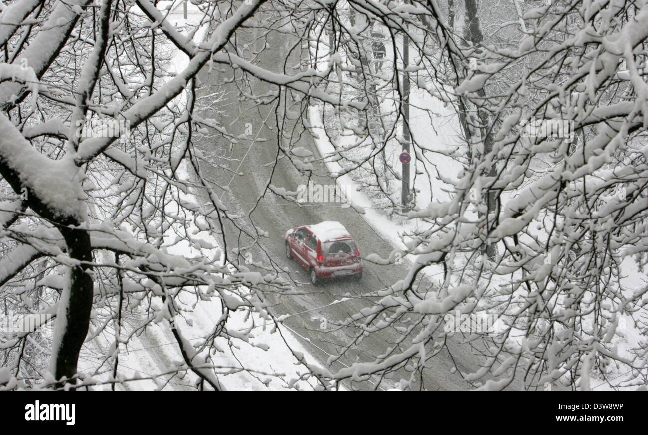 A red car drives on a snowy street in Munich, Germany, Wednesday, 24 ...