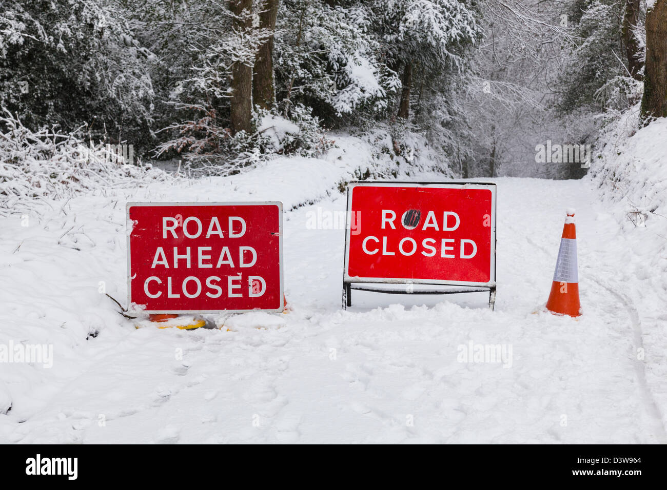 'Road ahead closed' signs and cones on a snow covered country lane ...