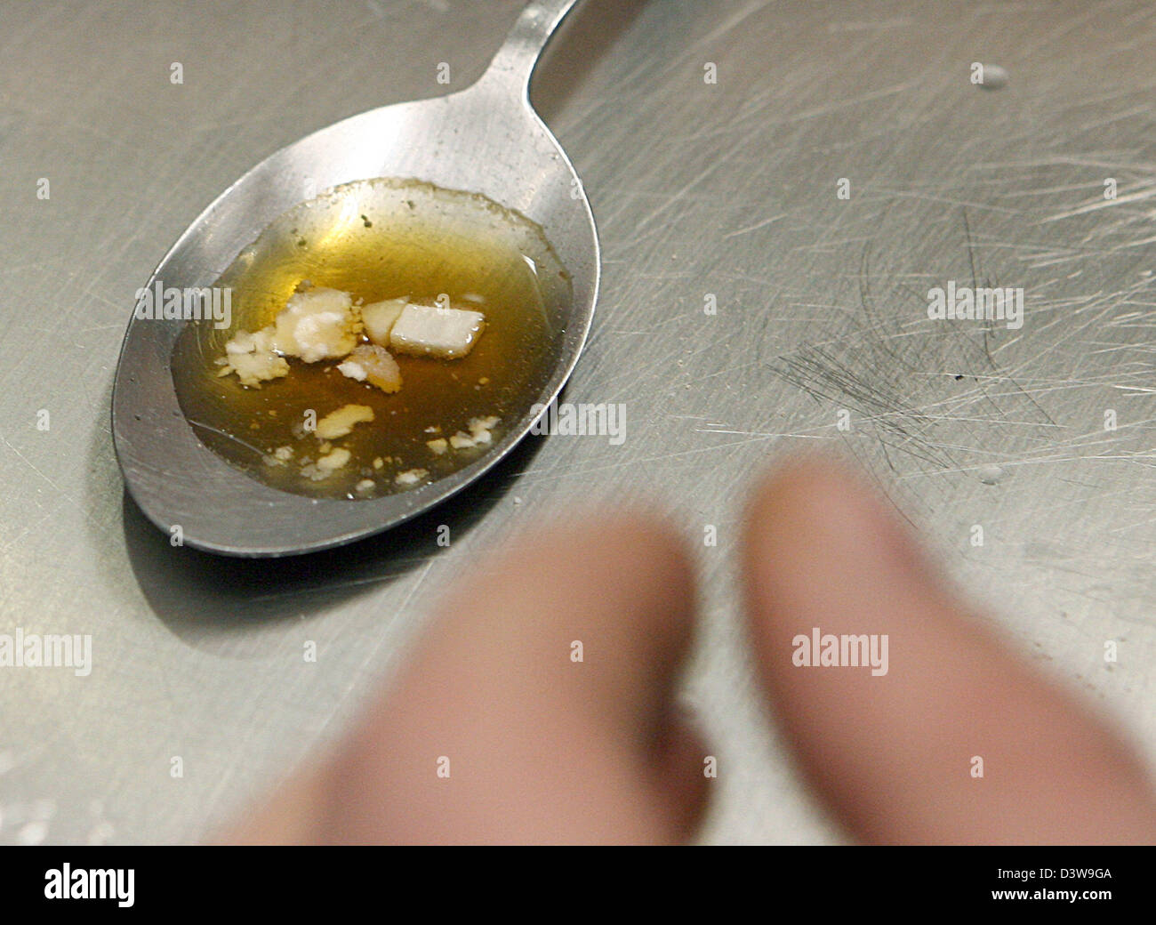 The hands of a young male drug addict disolve heroin on a spoon at the ...