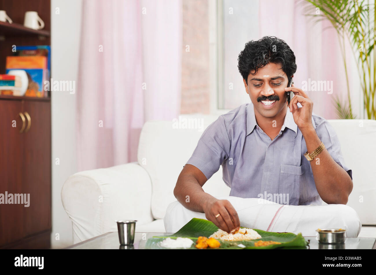 South Indian man having food and talking on a mobile phone Stock Photo ...