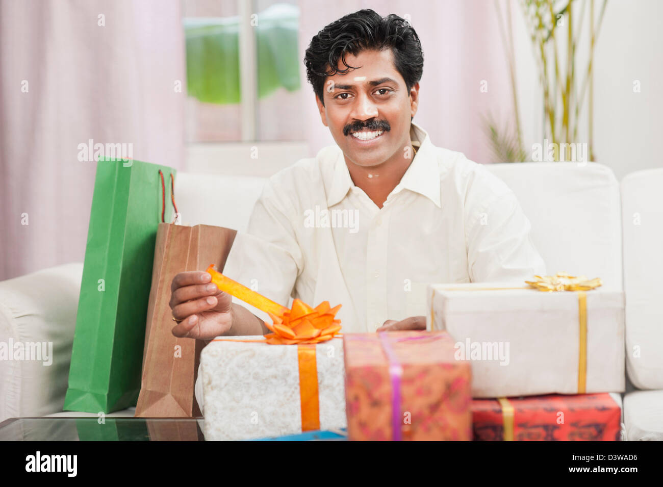 South Indian man smiling near gift boxes Stock Photo - Alamy