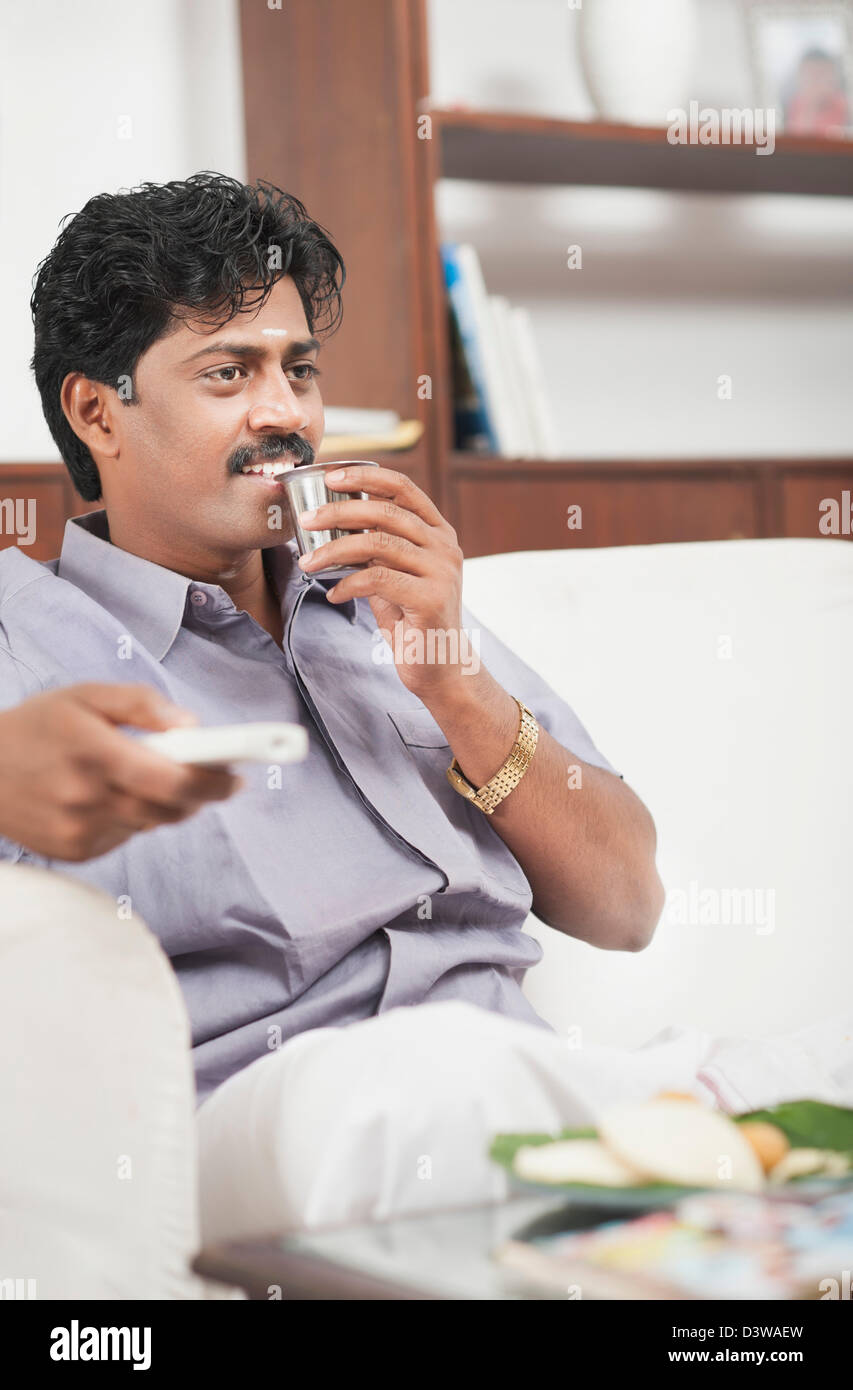 South Indian man watching TV and having tea Stock Photo - Alamy