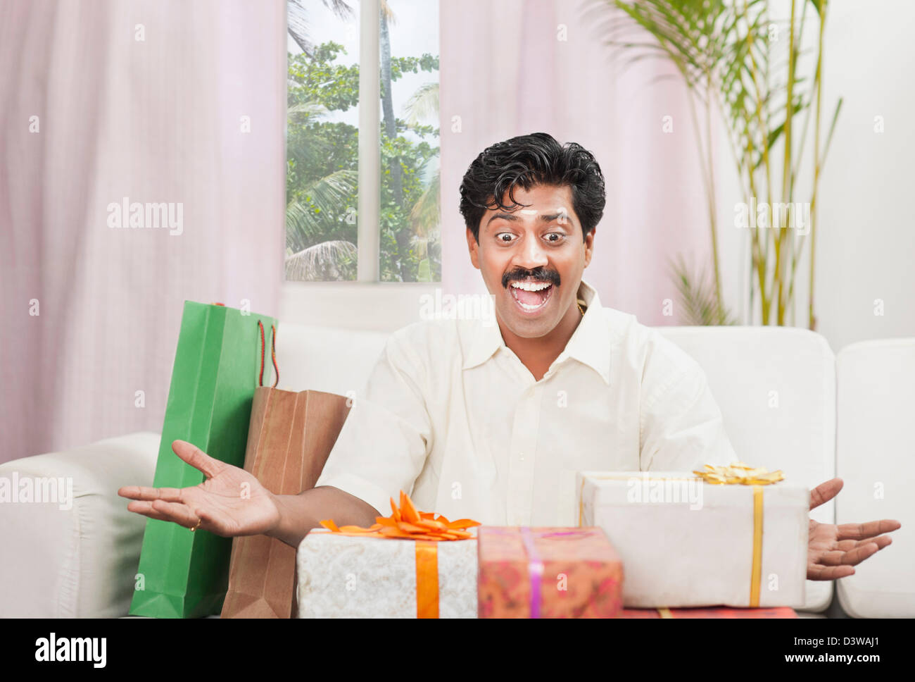 South Indian man smiling near gift boxes Stock Photo - Alamy