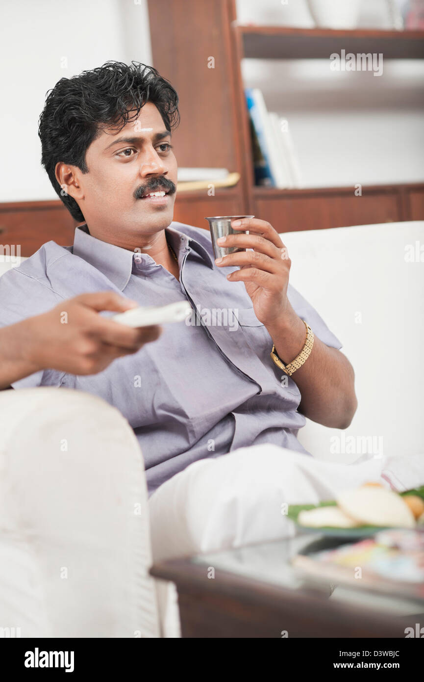 South Indian man watching TV and having tea Stock Photo - Alamy
