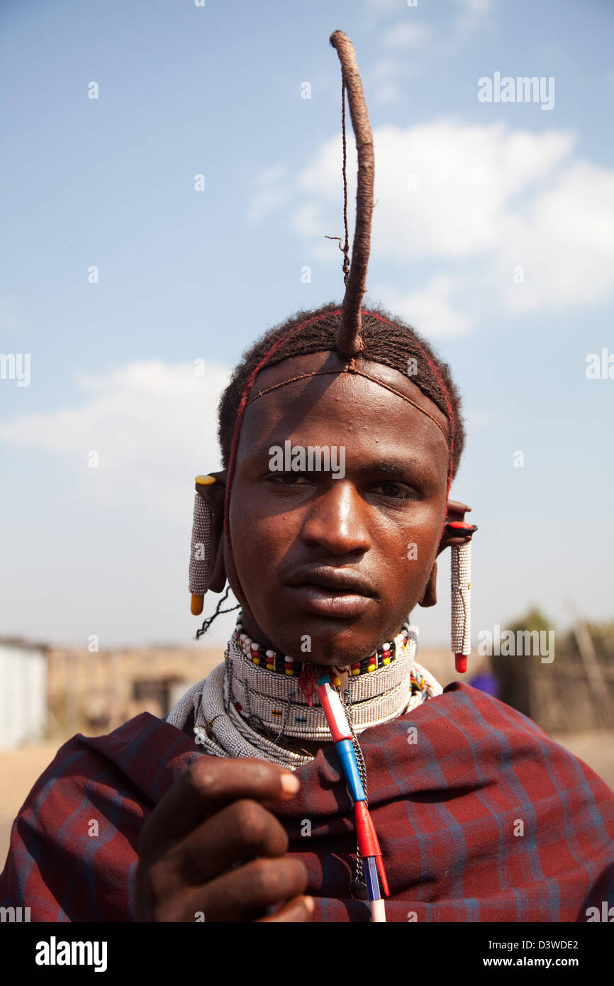 A young Maasai warrior in traditional head gear and Shukha Stock Photo ...
