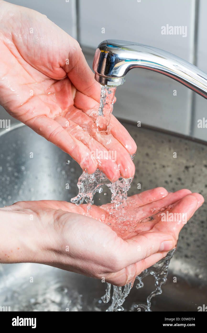 Person is washing her hands under running water from a tap in a bathroom. Symbol image for water ...