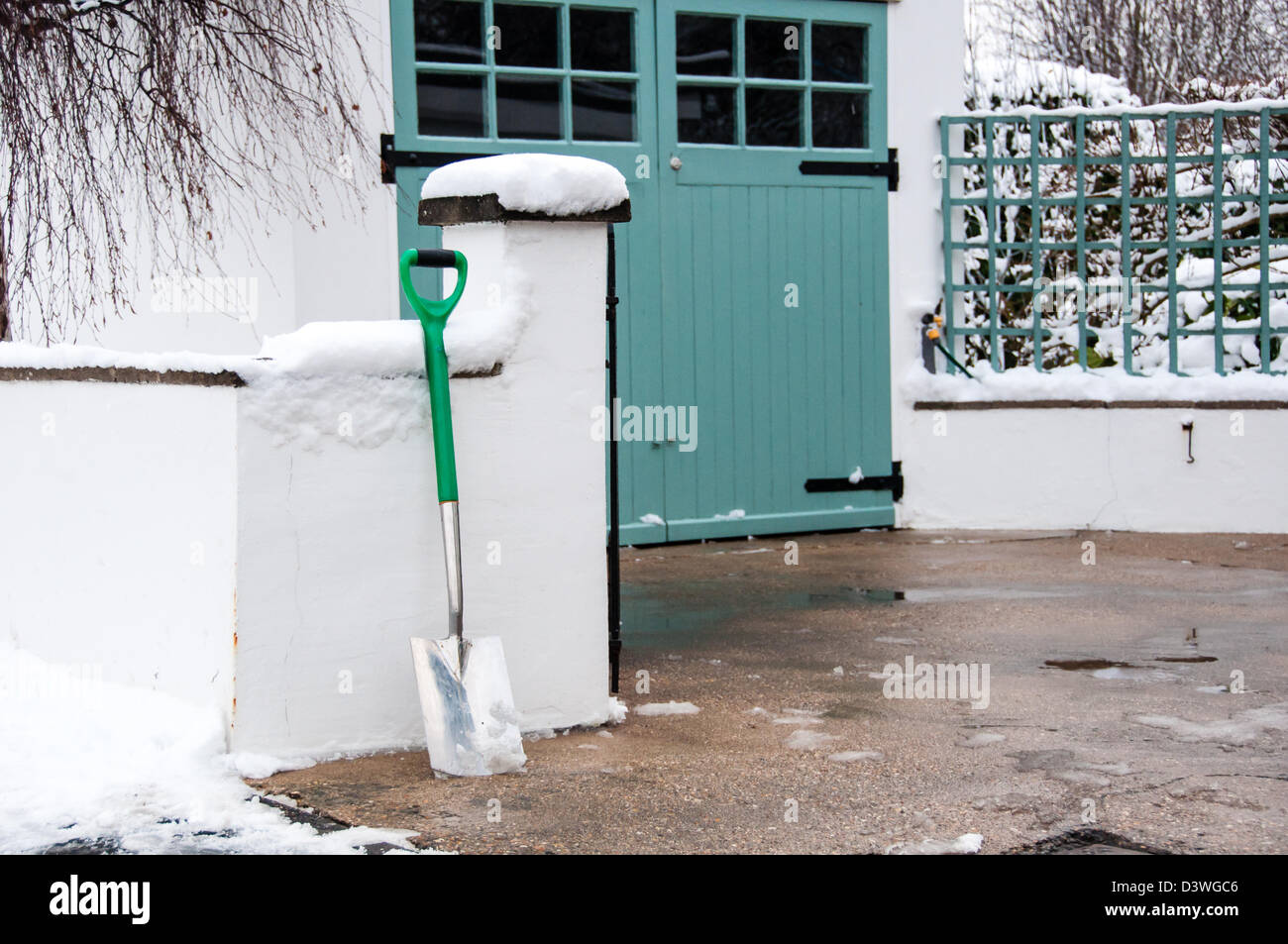 Shovel in front a snow covered path and a gate Stock Photo - Alamy