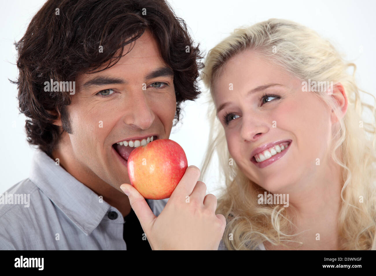 Woman looking at man eating an apple Stock Photo - Alamy
