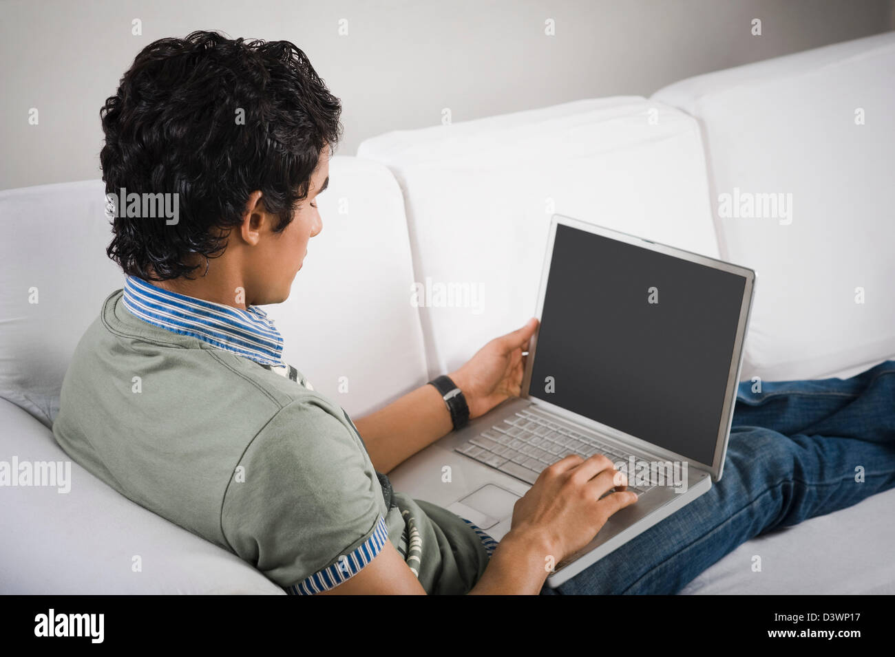 High angle view of a man sitting on a couch working on a laptop Stock ...