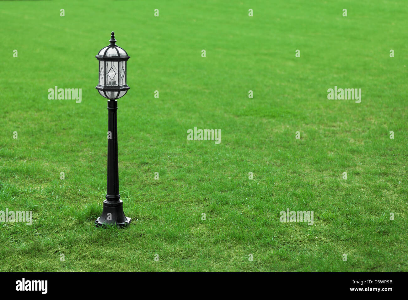 One metal black street lamp on green grass plot Stock Photo - Alamy