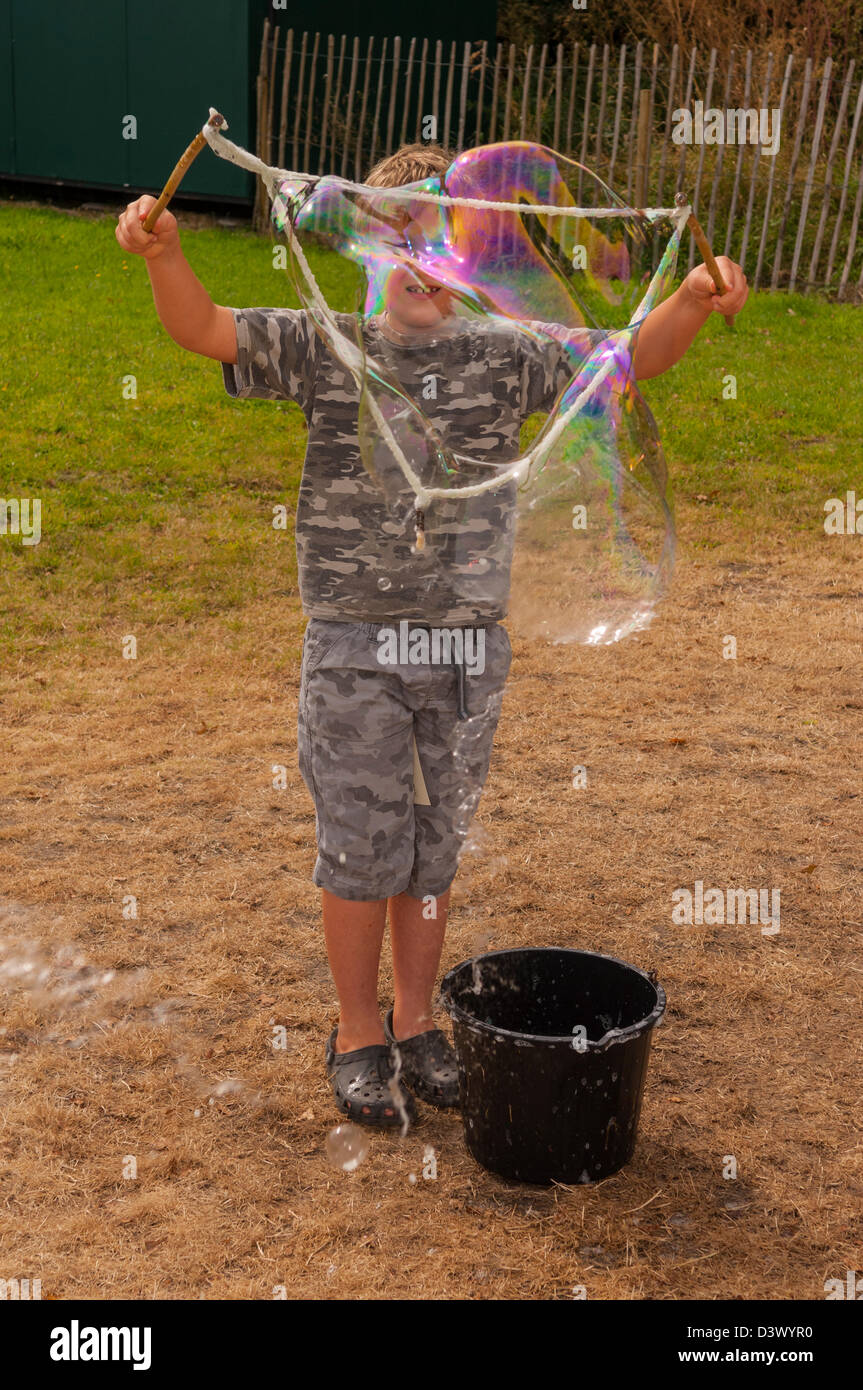 An 8 year old boy making a big bubble outdoors in the uk Stock Photo ...