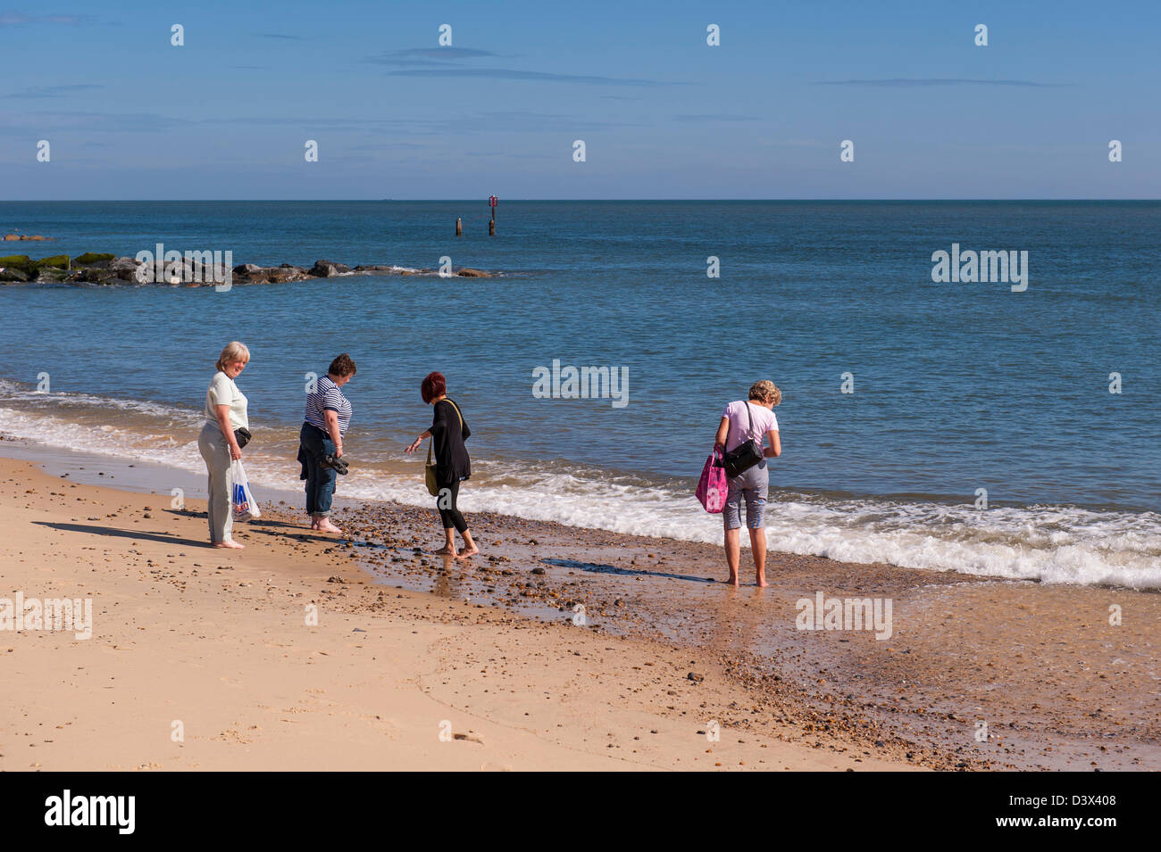 Four women paddling on the beach at Southwold , Suffolk , England ...